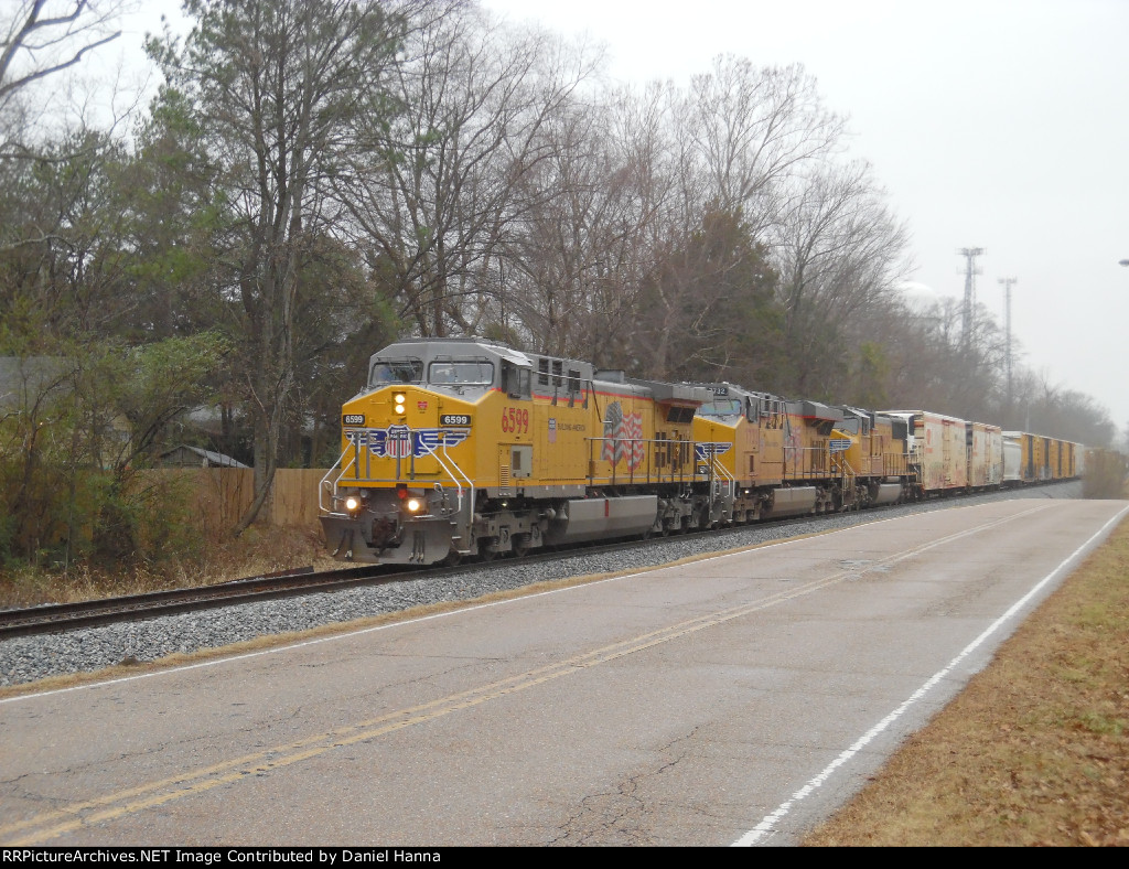 A trio of UP motors leads a long freight train east under rainy skies